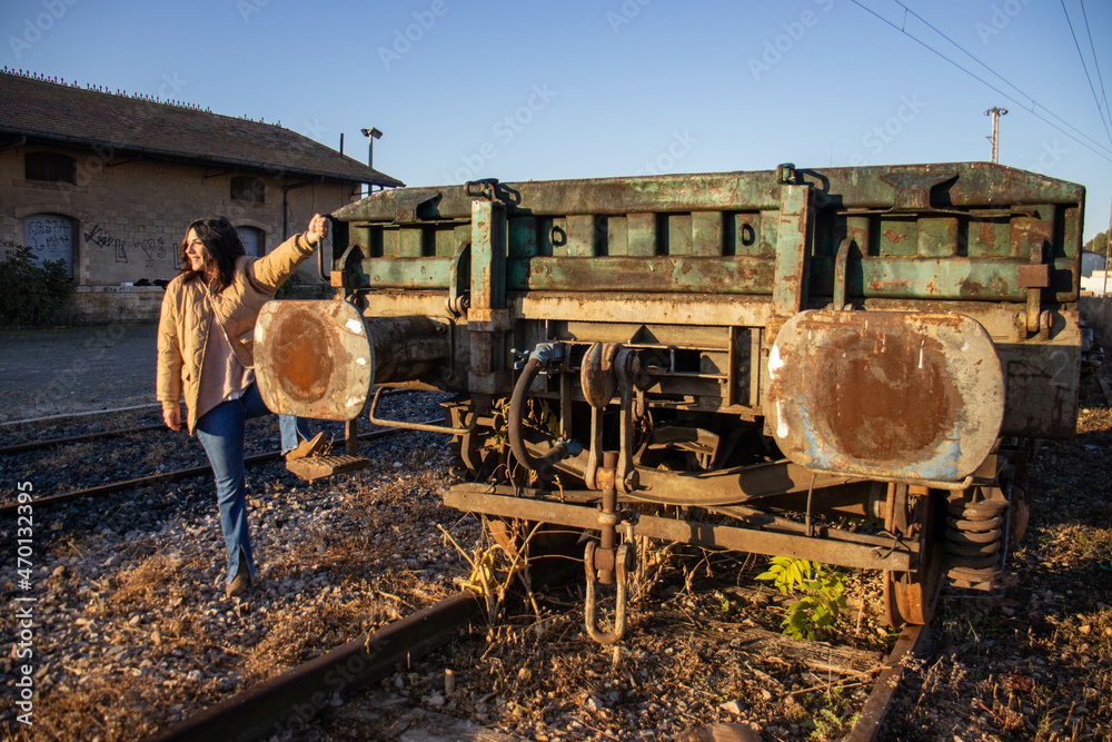 young model on railroad tracks, next to old and scrapped freight train ...