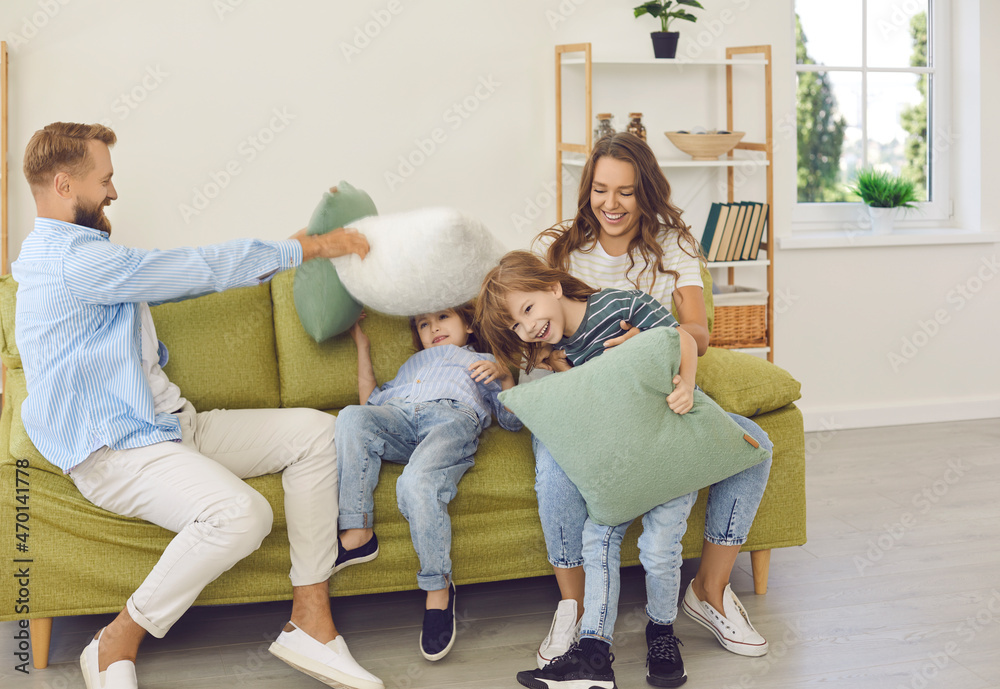 Young family of four having fun on sofa at home. Happy excited mom, dad ...