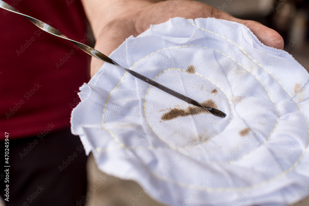 Dirty engine oil from a dipstick wiped on a white cloth pad, leaving a ...