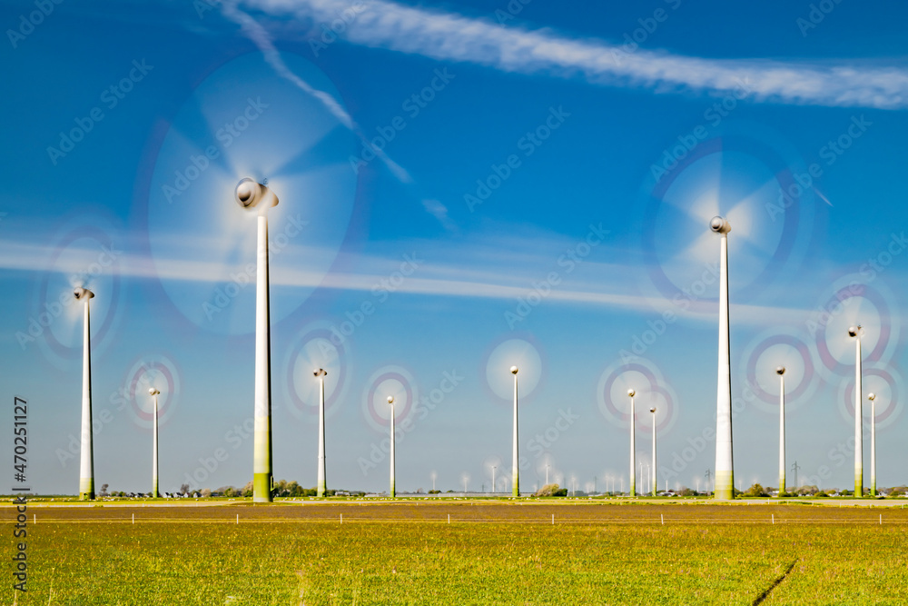 Rotating wind turbines of a wind park with condensation trails crossing ...