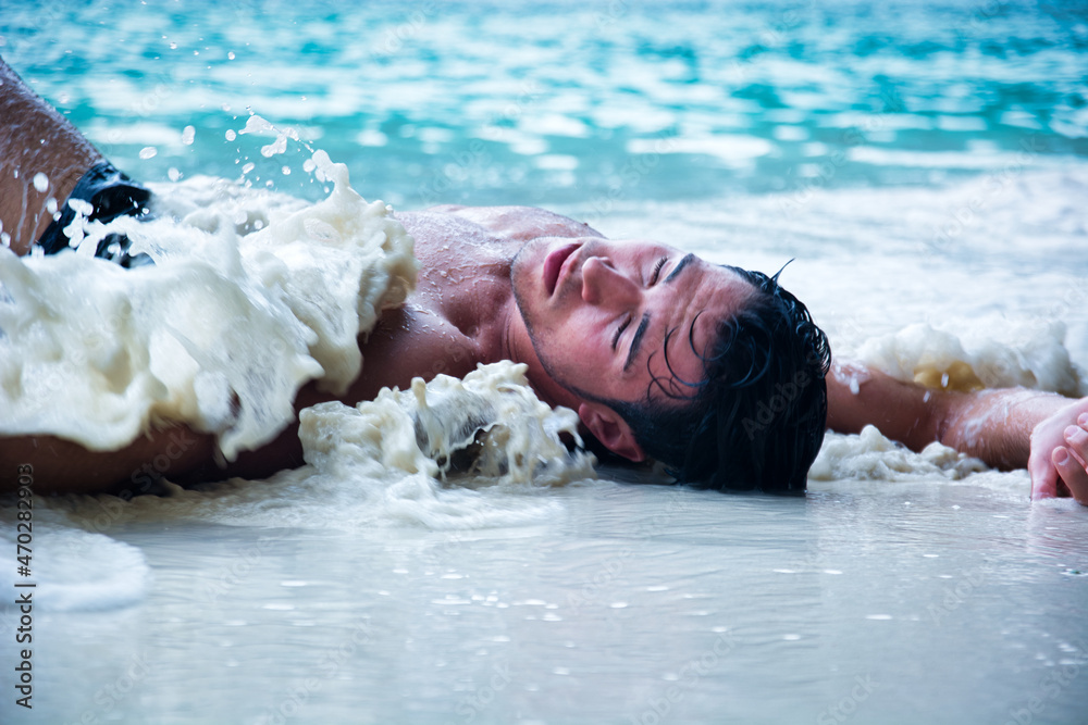 Shirtless young man on the beach lying on sand Stock Photo | Adobe Stock