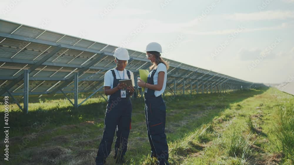 Multi-ethnic female team coworking on solar station. Large photovoltaic ...