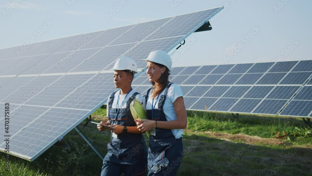 Solar plant workers. Multi-race female couple engineer with assistant ...