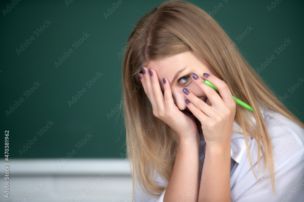 Portrait of a young shame embarrassed female student studying in school ...