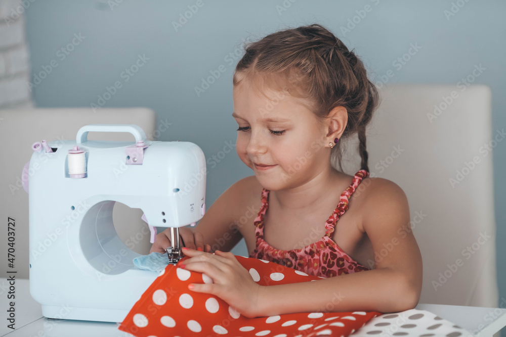 7 years old child studying work with a modern sewing machine. Hobby ...