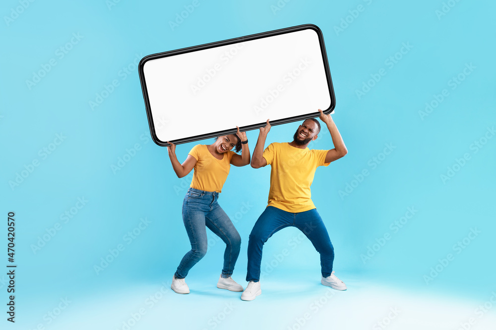 Emotional black couple holding big heavy smartphone with empty screen ...