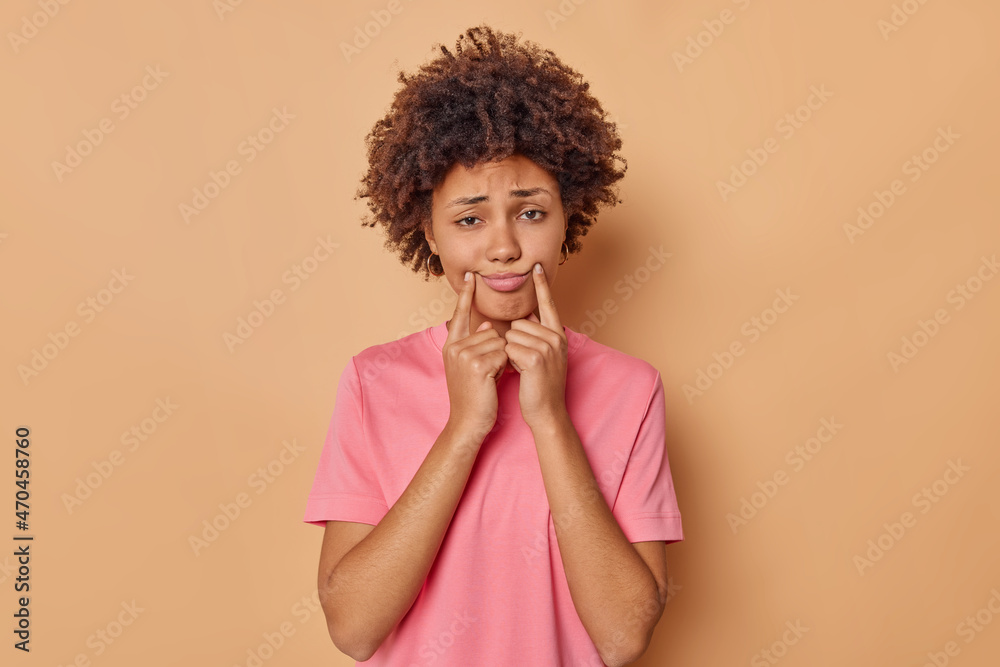 Foto de Photo of displeased young woman stretches mouth in forced smile ...