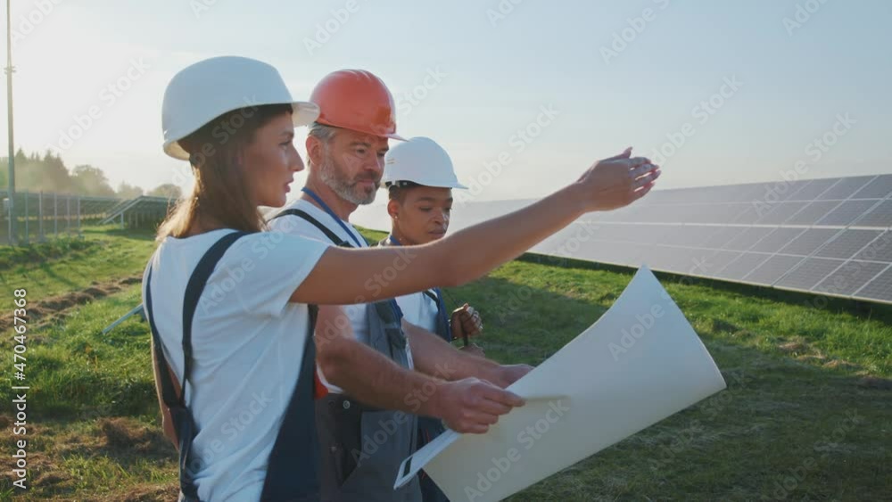 Multi-ethnic architect group walking on ecological solar station field ...