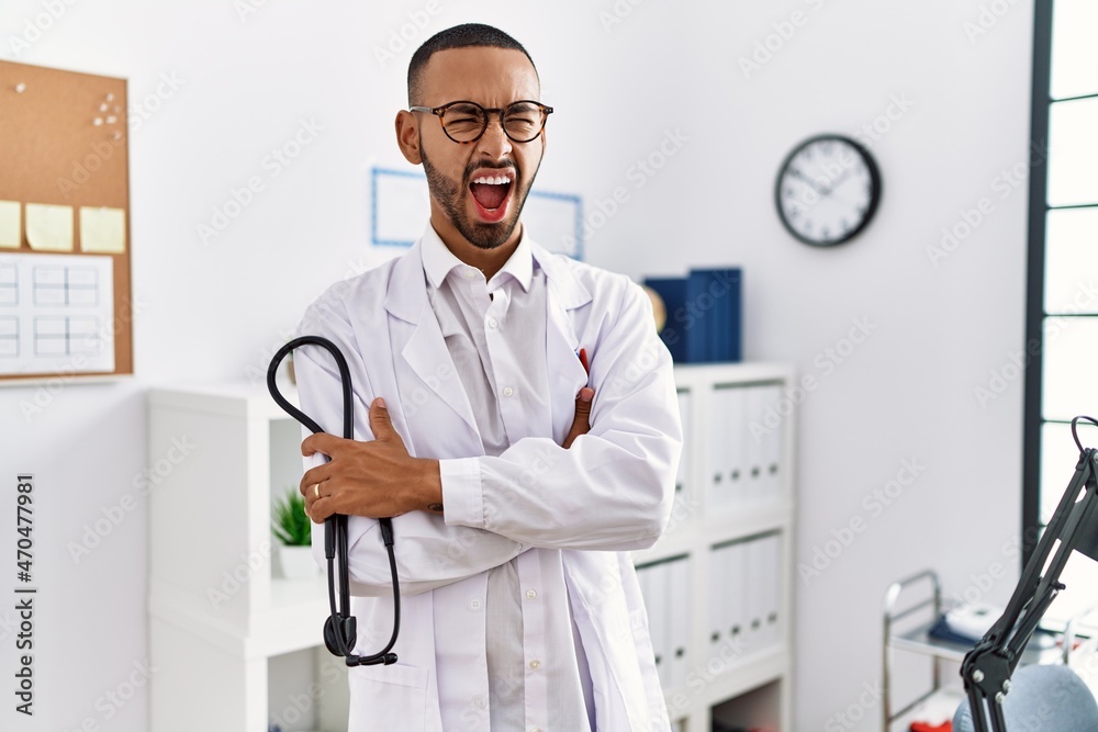 African american doctor man holding stethoscope at the clinic angry and ...