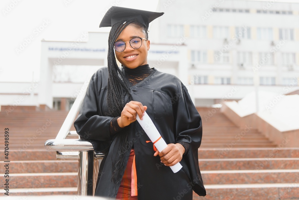 pretty african college student in graduation cap and gown in front of ...