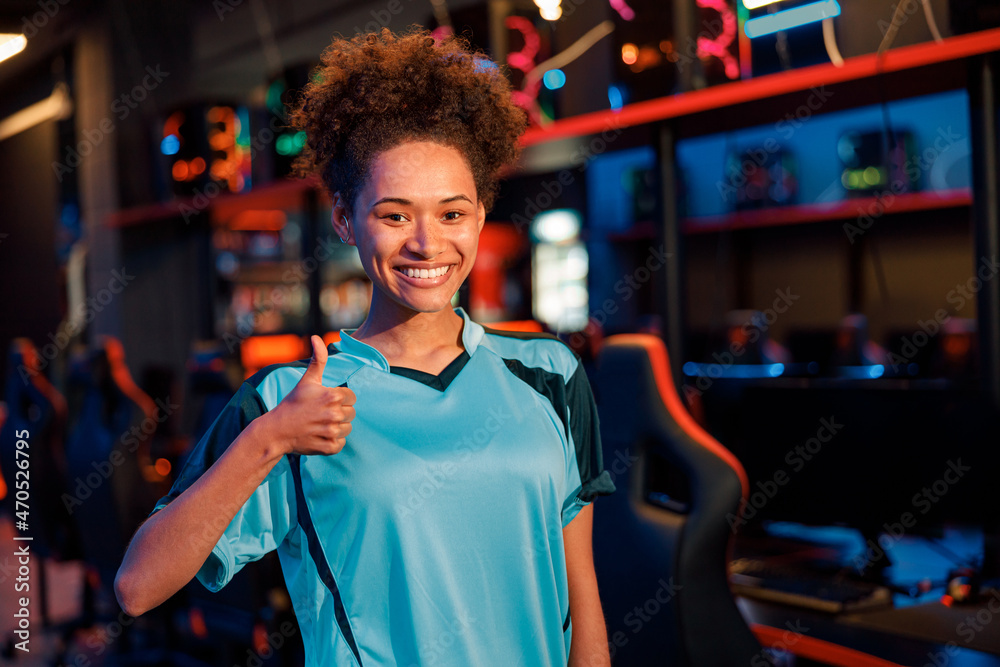 Young female esports gamer giving thumbs-up sign with cheerful facial ...