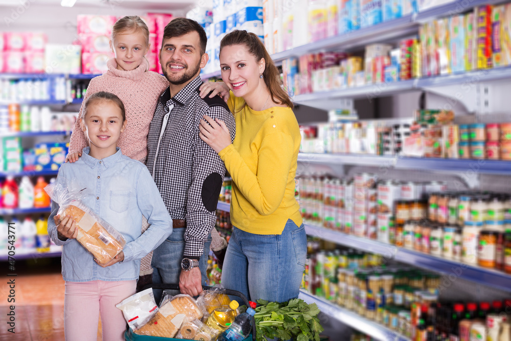 Happy young parents with two little girls with purchases during family ...