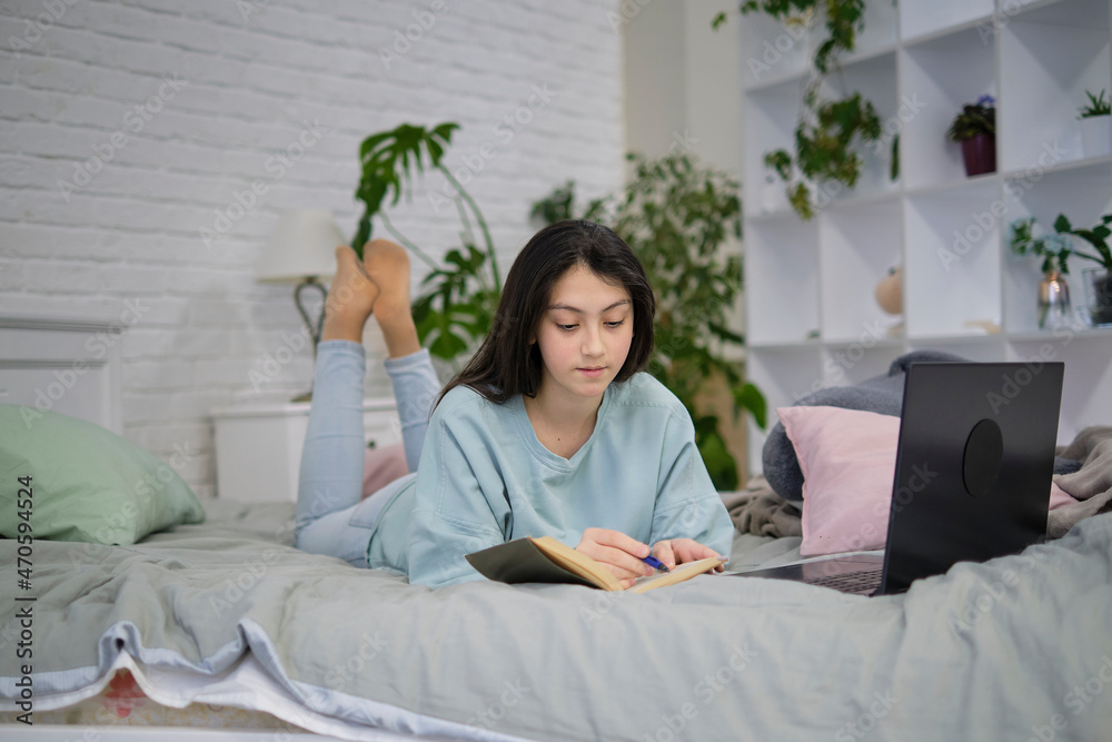 Teenage girl doing homework on the bed. teen girl school student write ...
