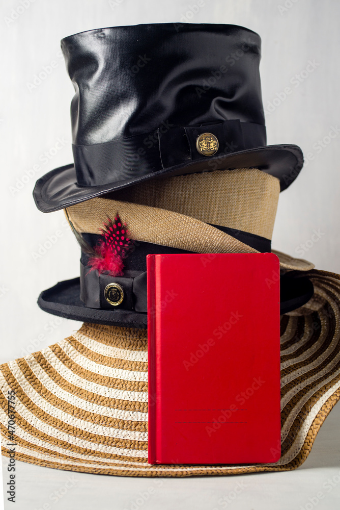 Stack of hats, various type of hats and a red book isolated on white ...