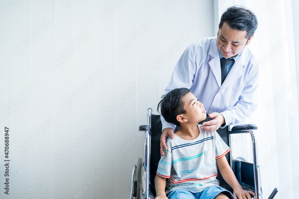 Male doctor standing, caring and cheering for a boy patient sitting in ...