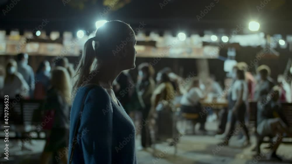 Wide shot - a young, blonde girl walks through a crowd of people on a ...