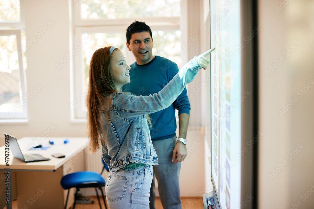 High school student using smart board with her teacher in the classroom ...