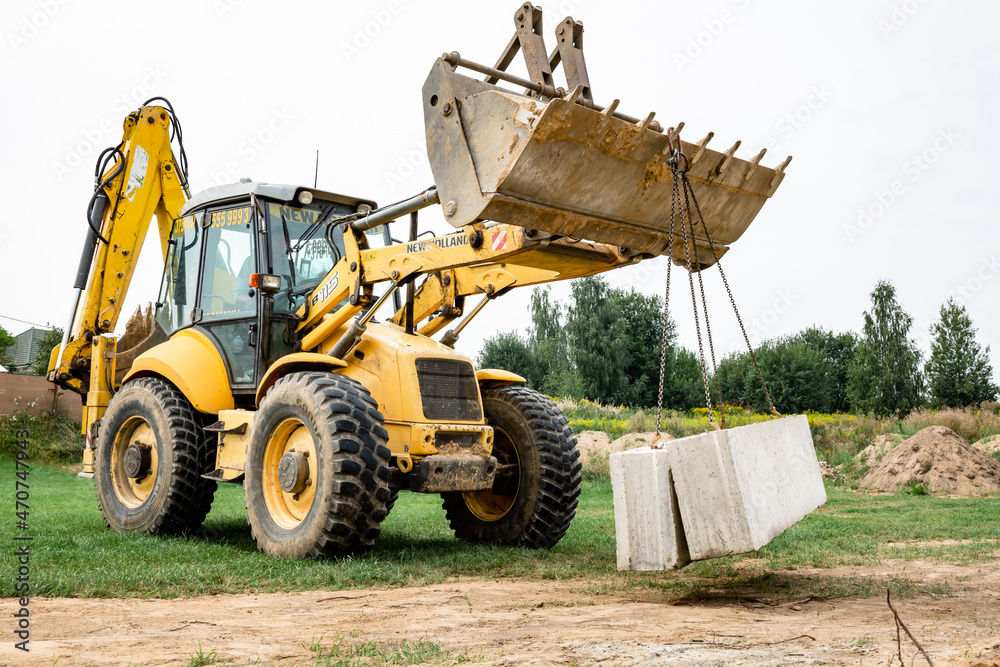 Wheel loader. Excavator install the foundation blocks into a trench ...