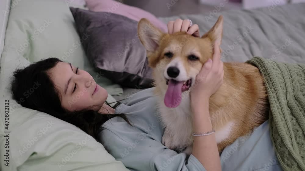 young teenage girl relaxing in bed with her dog. happy teenager girl ...