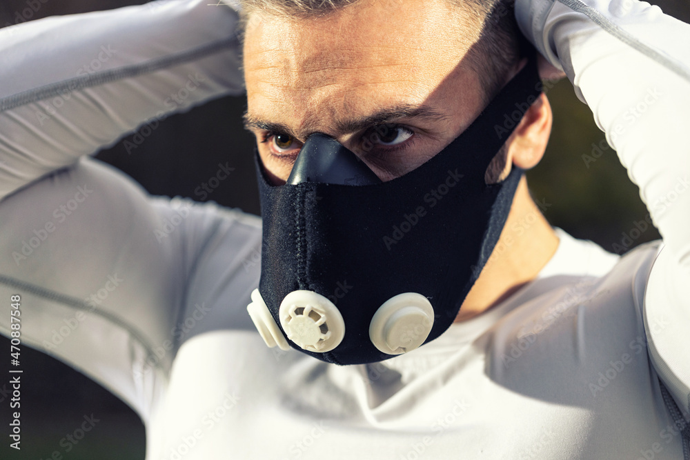 Strong muscular athlete putting on his fitness breathing mask and ...