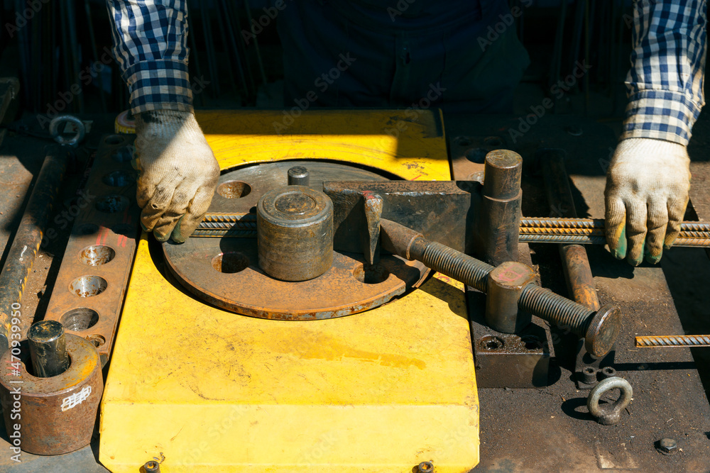 Hands of a worker at work at the armature bending machine. Rebars with ...