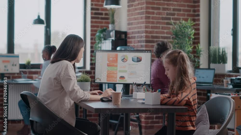 Working mother planning project on computer while colleague talking to ...
