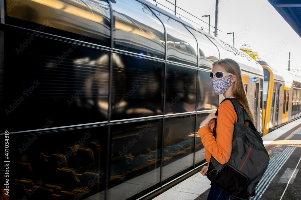 Foto de Teenage girl wearing face mask waiting for the train on the ...