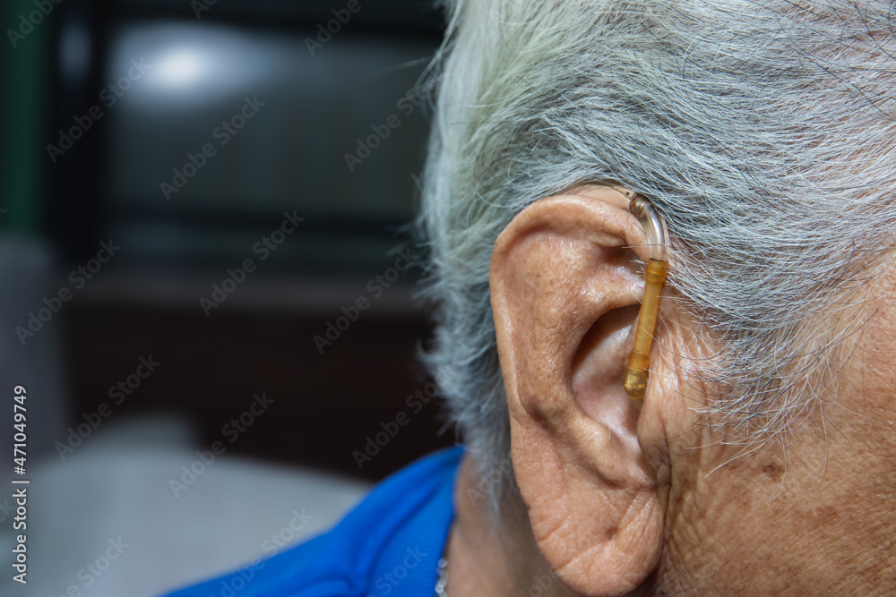 Asian elderly or senior woman wearing a hearing aid,close up hand of ...
