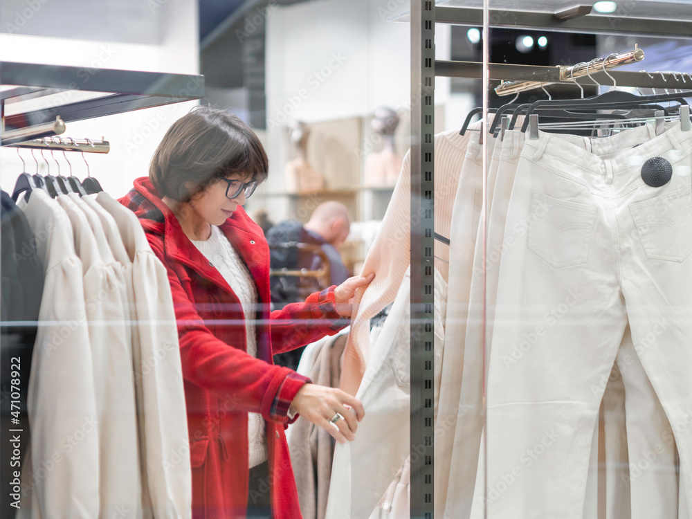Woman chooses dress at clothing store. Casual trousers hanging on ...