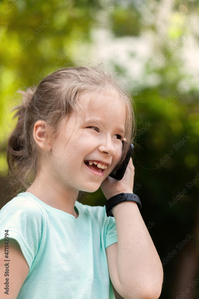 Happy cheerful elementary school age child, girl talking on her mobile ...