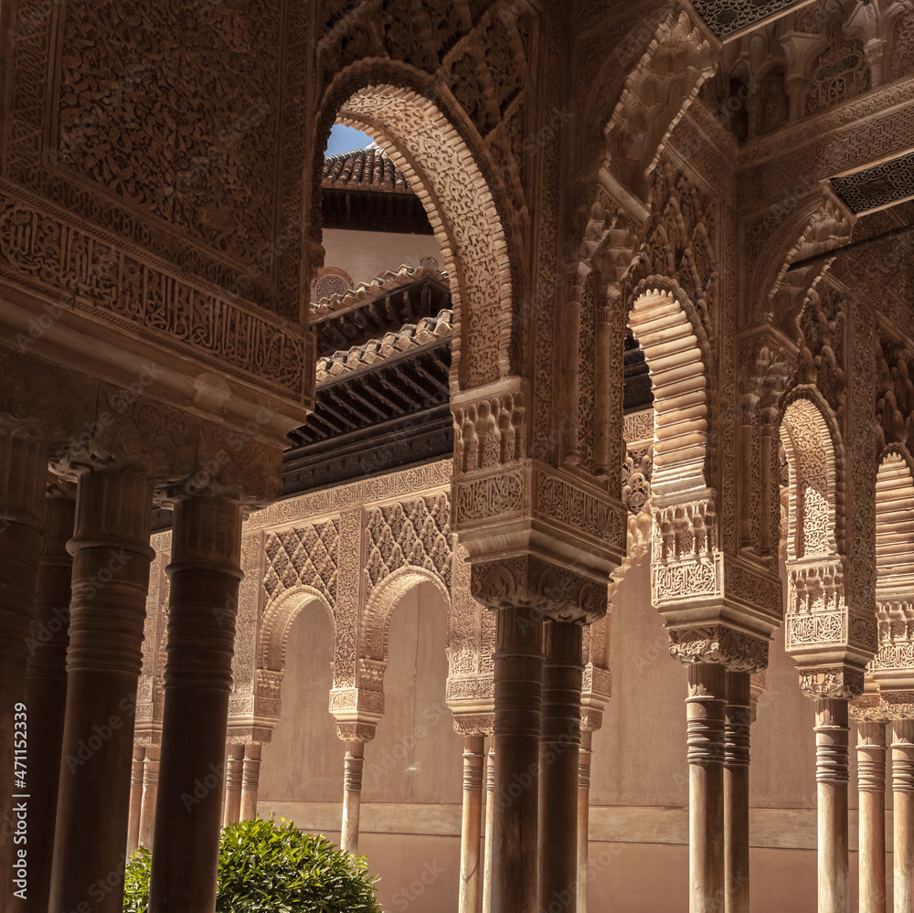 Stone pillars and arches of the Alhambra Palace with carved patterns ...