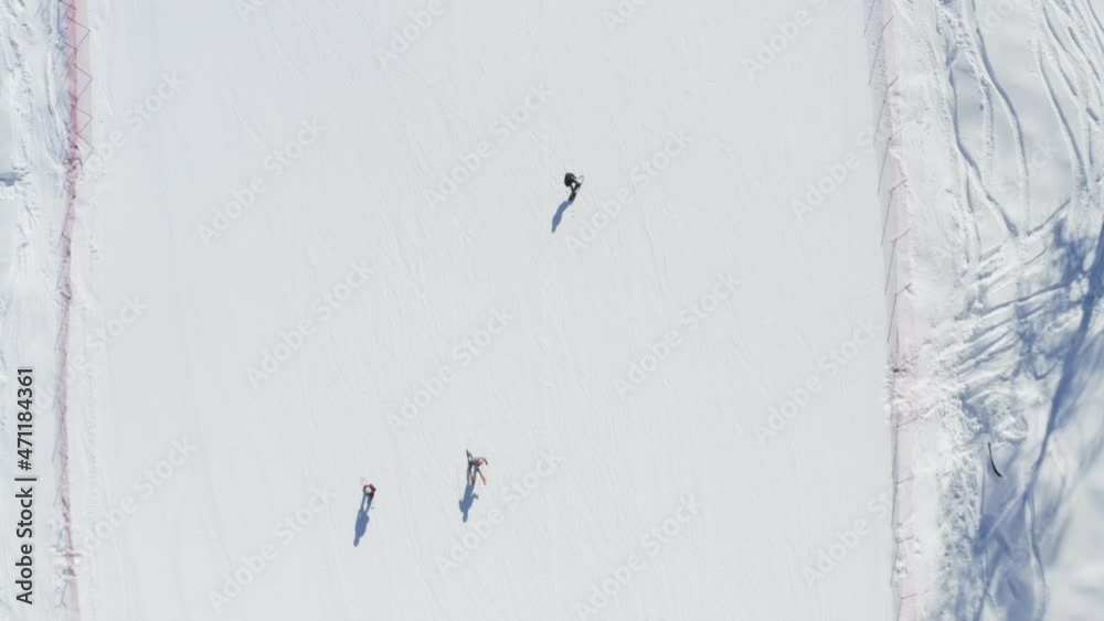Aerial bird's eye view of a ski slope. Skiers and snowboarders going ...