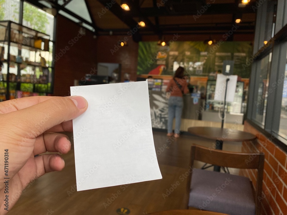 Hand holding blank white cue card with blurred cashier counter coffee ...