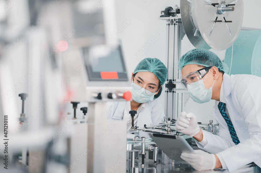 Both male and female Asian scientists are outfitted with protective ...