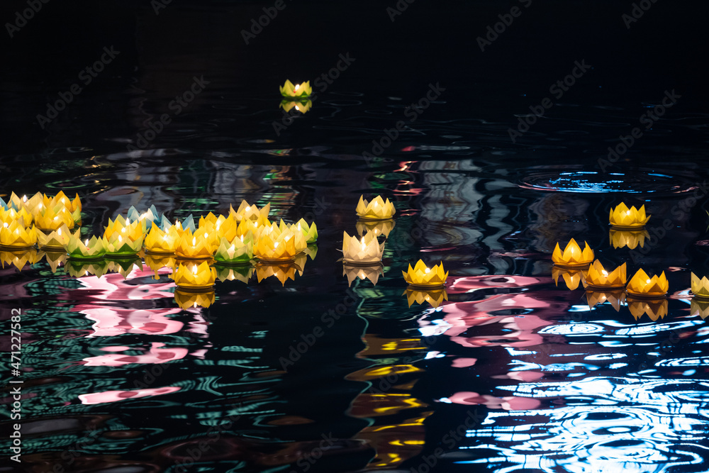 Floating colored lanterns and garlands on river at night on Vesak day ...