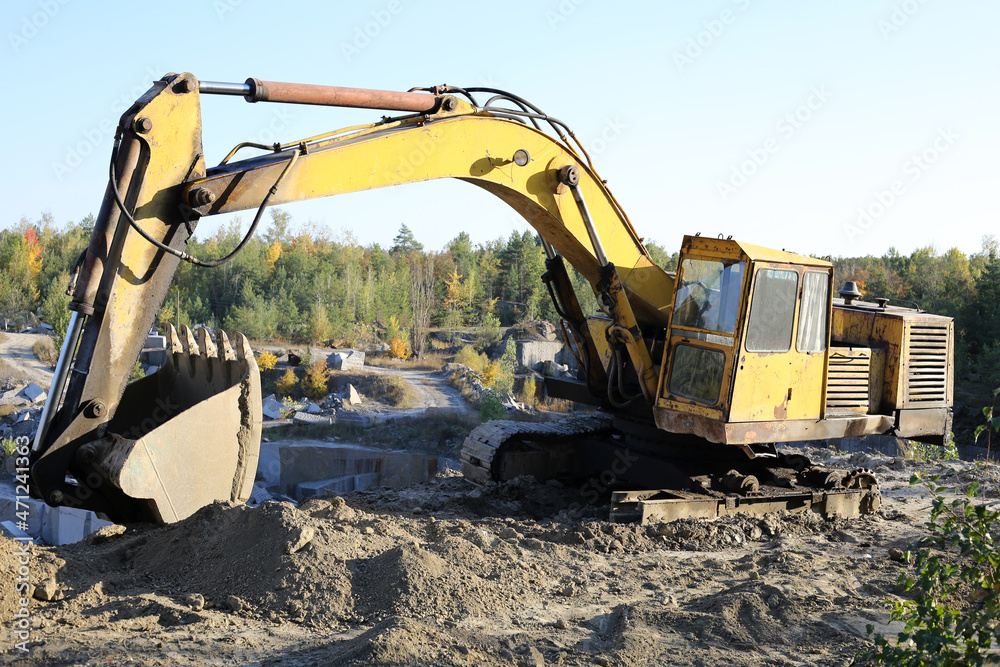 A large diesel excavator is stuck in the mud at a granite quarry. Stock ...