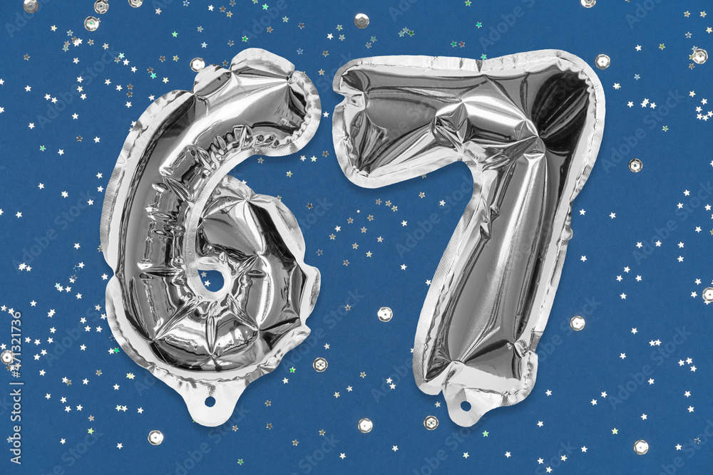 Silver foil balloon number, digit sixty seven on a blue background with ...