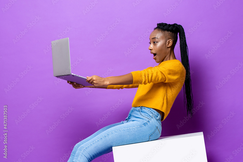 Excited African American woman holding and watching laptop computer ...