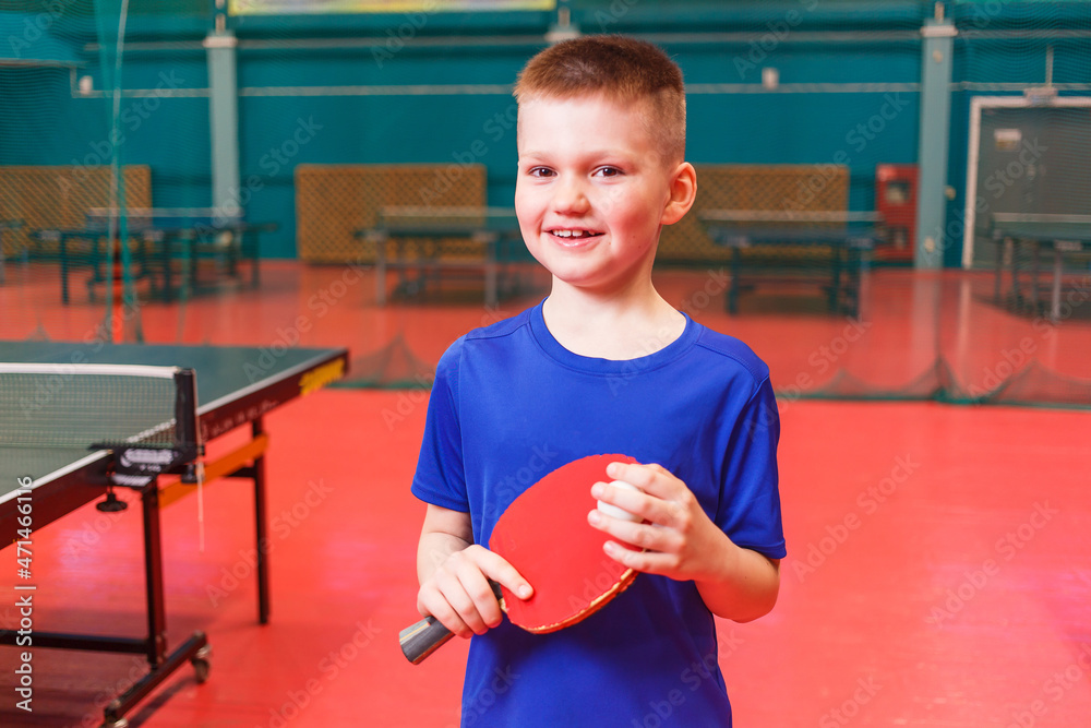 short - haired eight-year-old boy holds a racket and a table tennis ...