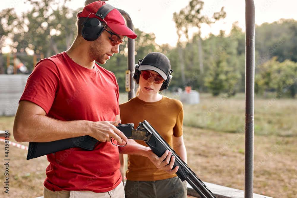 handsome caucasian man and young woman checking details of weapon ...