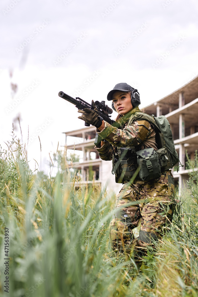 young slender caucasian woman soldier in military gear shooting with ...