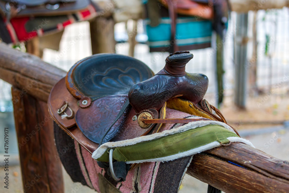 Saddle on fence against the wooden wall. Sport leather saddle, harness ...