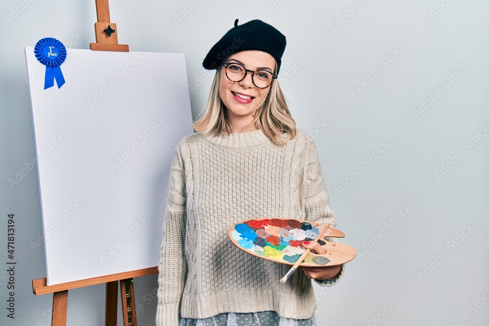 Beautiful caucasian woman drawing with palette on easel stand winner ...