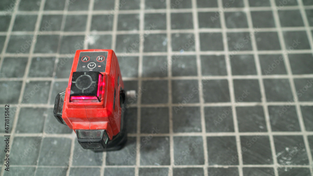 Setting the laser level. Ceramic tiles and tiler tools. Worker hand ...