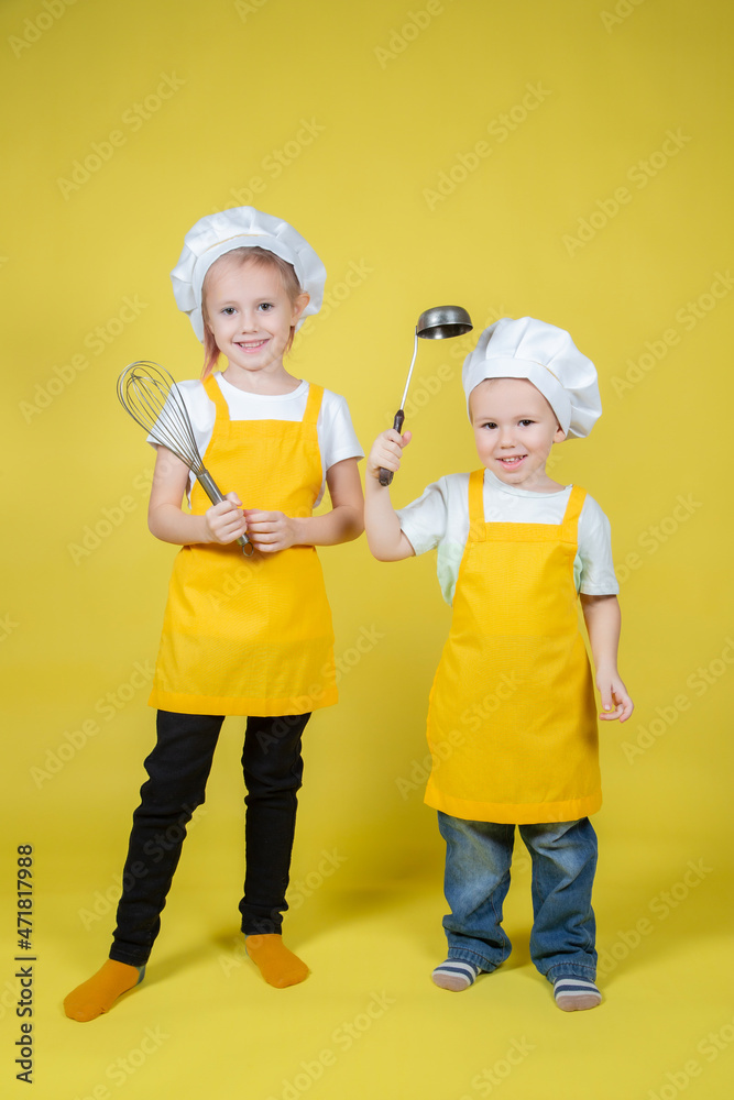 Children playing chefs, boy and girl in an apron and a chef's cap are ...