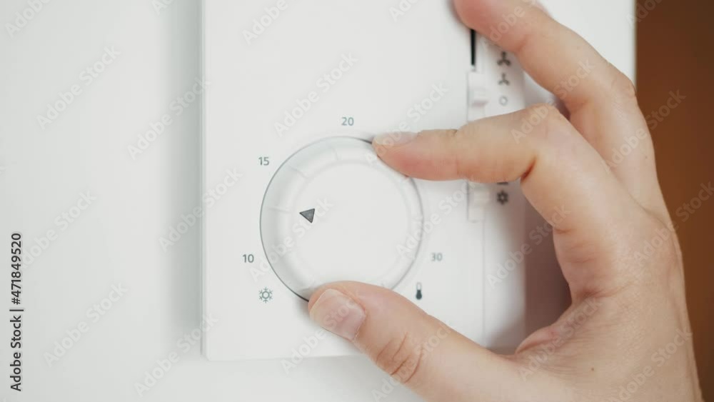 Hand setting up the temperature using a smart thermostat climate ...