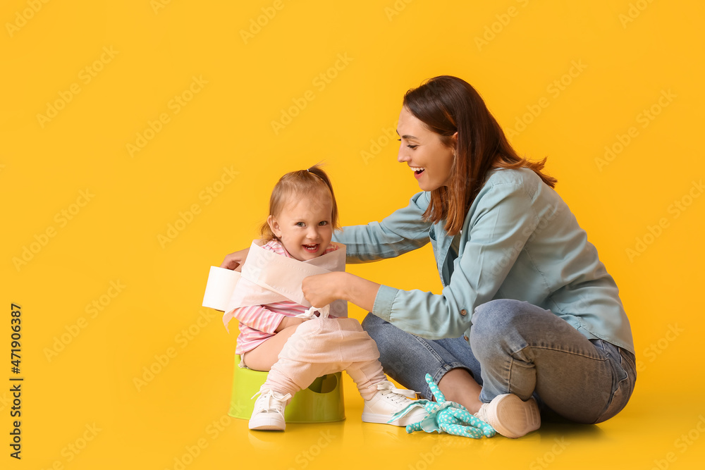 Mother potty training her little daughter on color background Stock ...