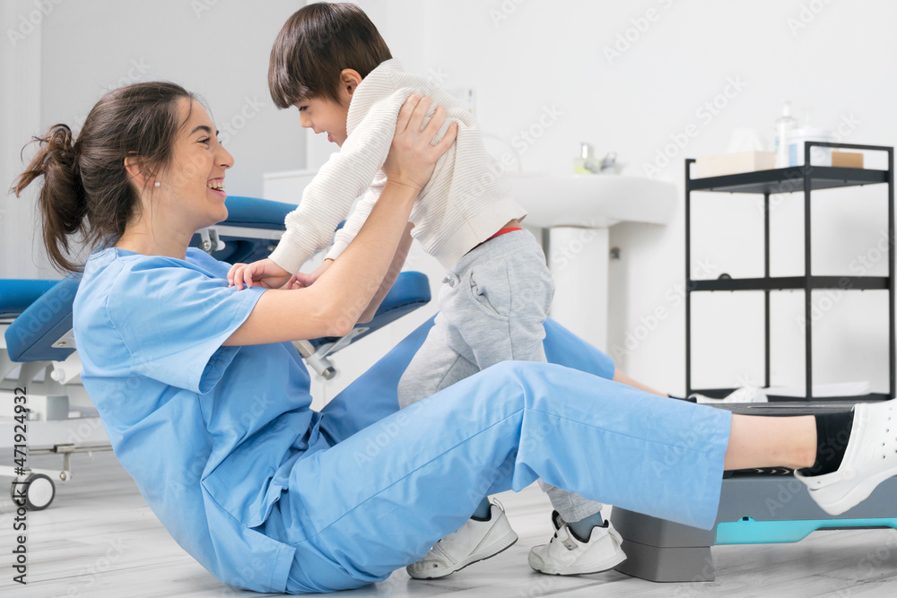 Physiotherapist hugging a little boy with a disability at ...