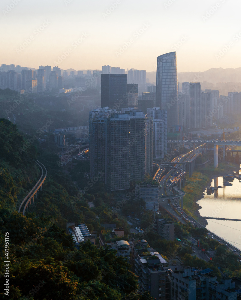 At sunset, in Chongqing, China, cars stream along the river banks and ...
