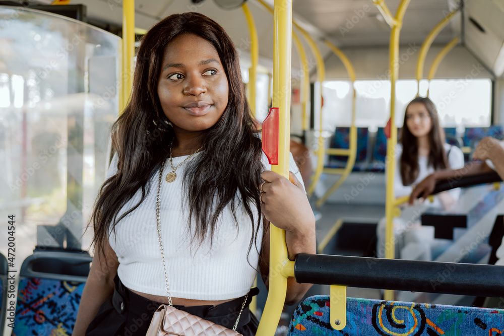 Thoughtful dark-skinned woman is riding bus, looking out window ...